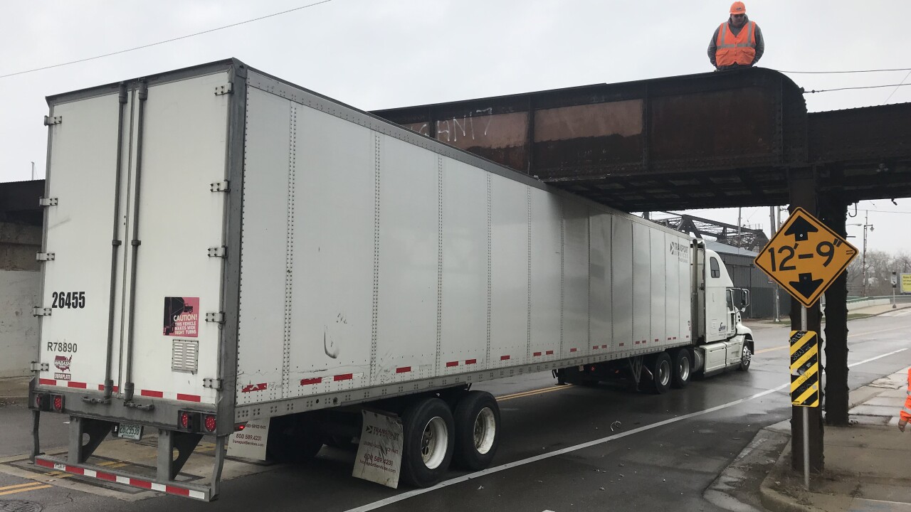 Semi-truck gets stuck under bridge due to obstructed sign